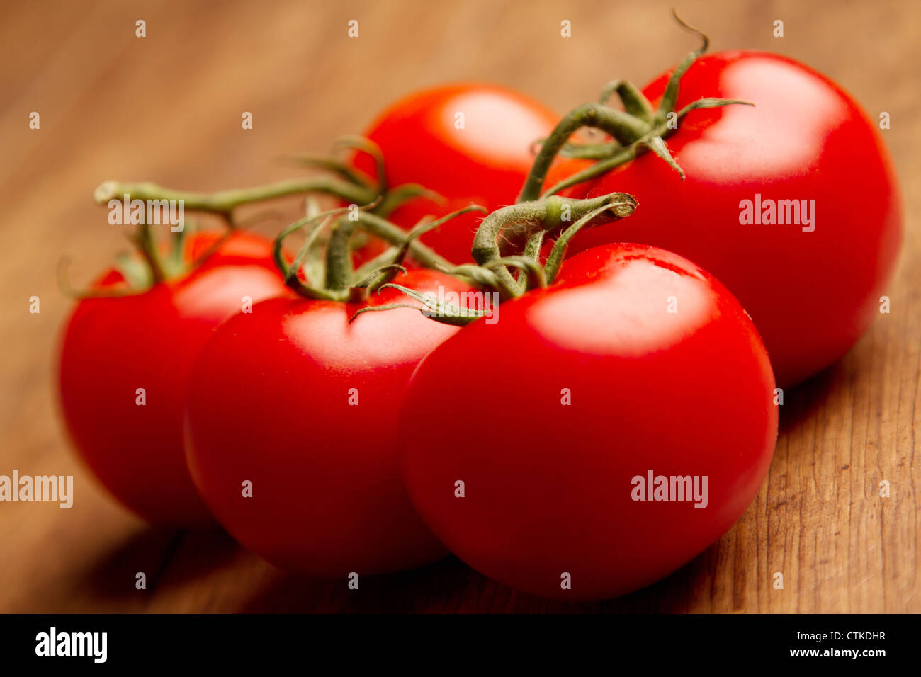 Five large vine tomatoes placed on a wooden background Stock Photo - Alamy