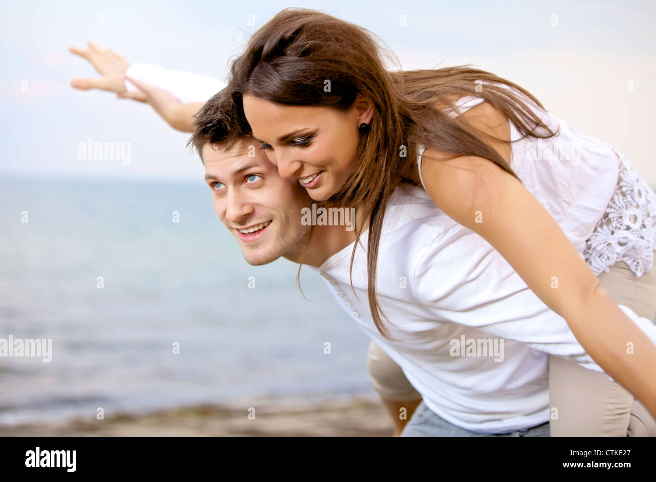 Portrait Of A Handsome Guy Carrying His Girlfriend On His Back Against