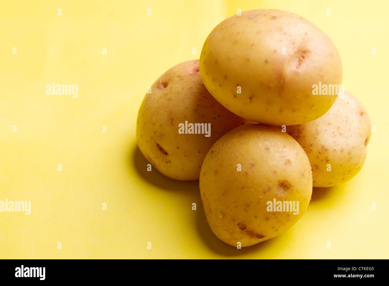 Four potatoes set on a bright yellow background Stock Photo - Alamy