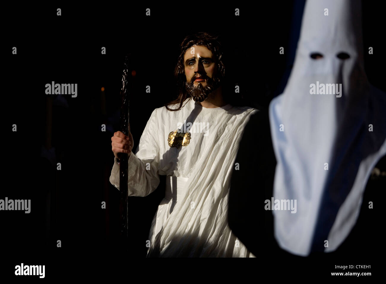 A masked man dressed as Jesus Christ walks near a penitent during an ...