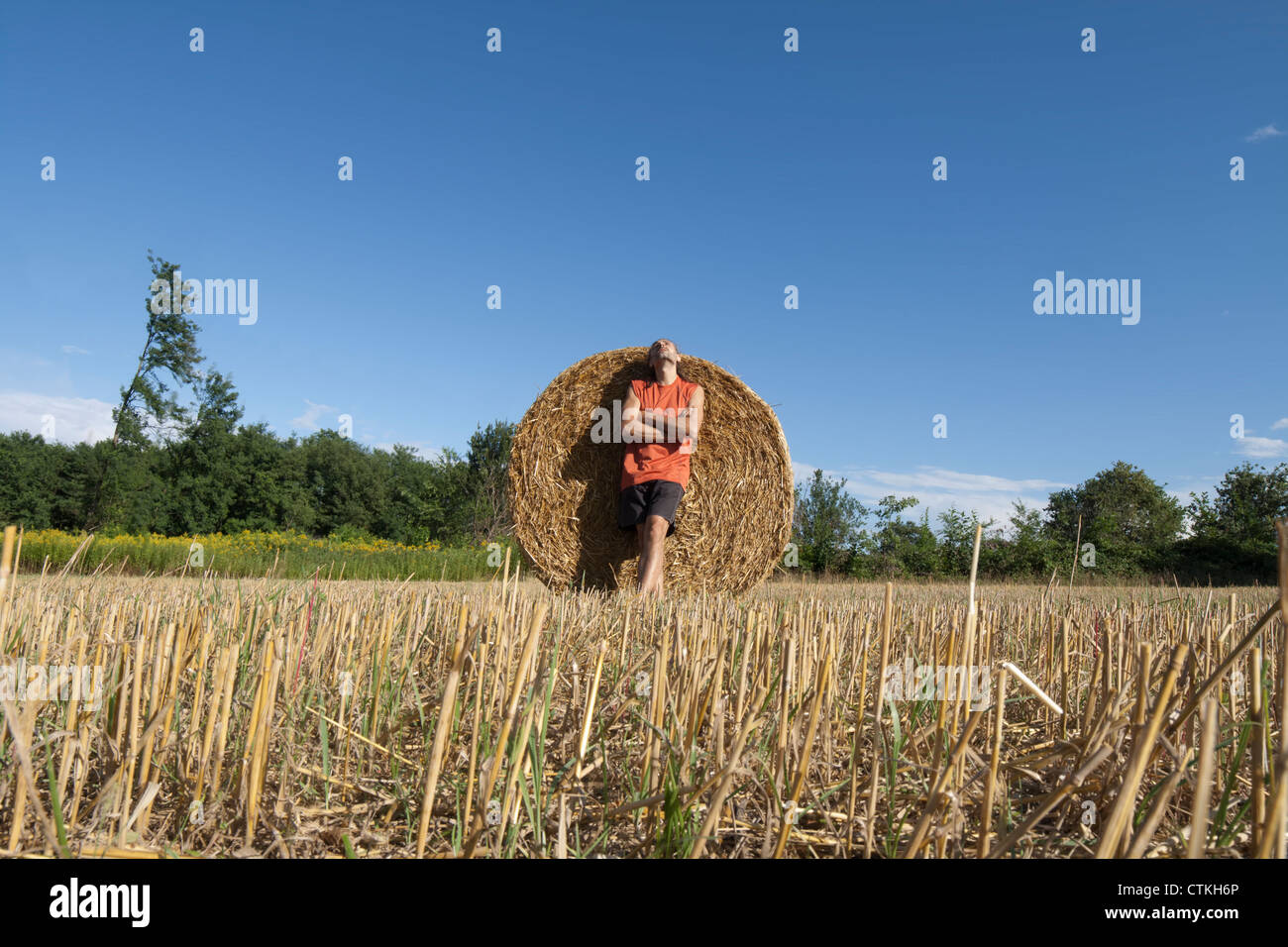 man leaning on hay bale in summer field Stock Photo - Alamy