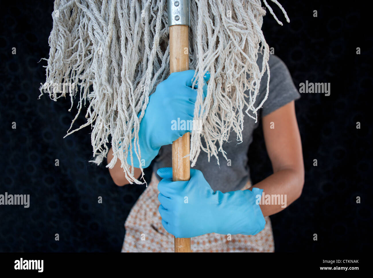 A person holding a large mop and wearing blue rubber gloves Stock Photo ...