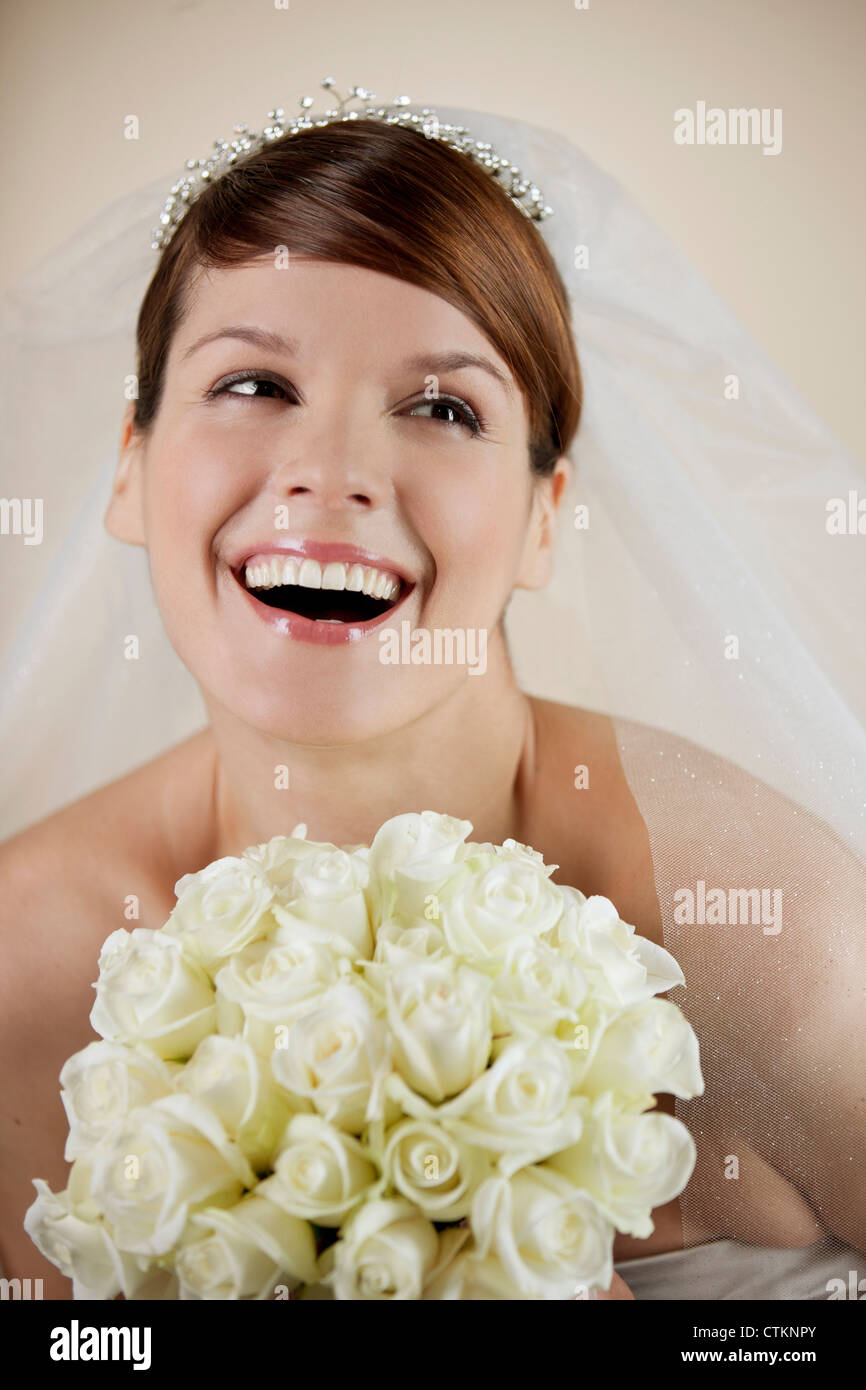 A young bride holding a bouquet of white roses, laughing Stock Photo ...