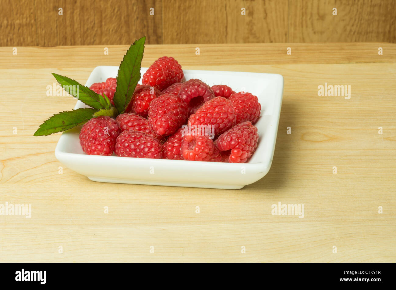 Red raspberries and green mint on a white plate Stock Photo - Alamy