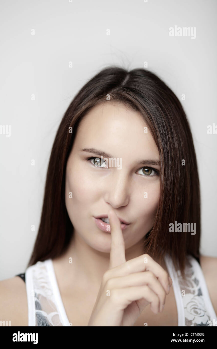 Woman making a keep it quiet sign with her finger shot on white ...