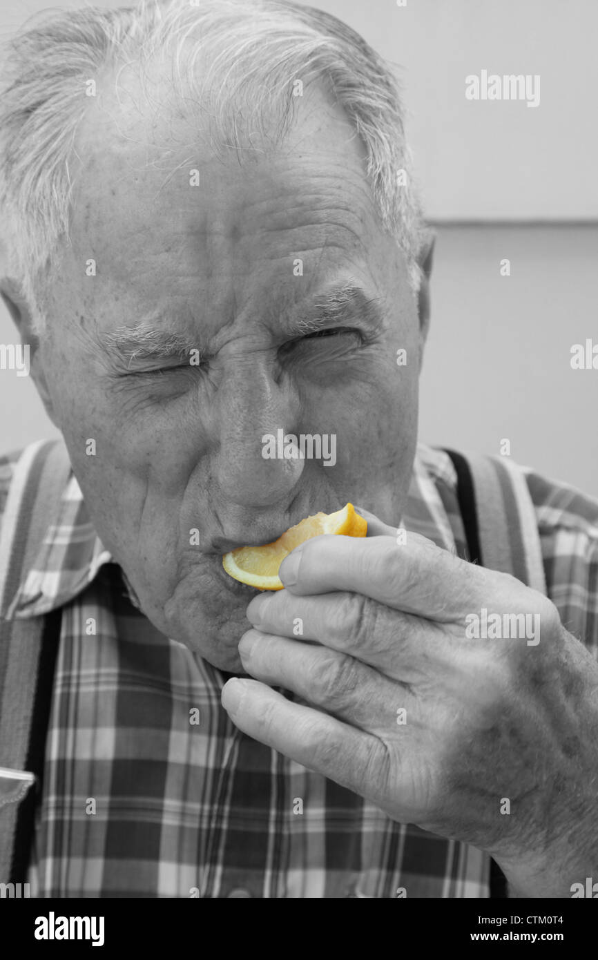 Senior man eating lemon Stock Photo - Alamy