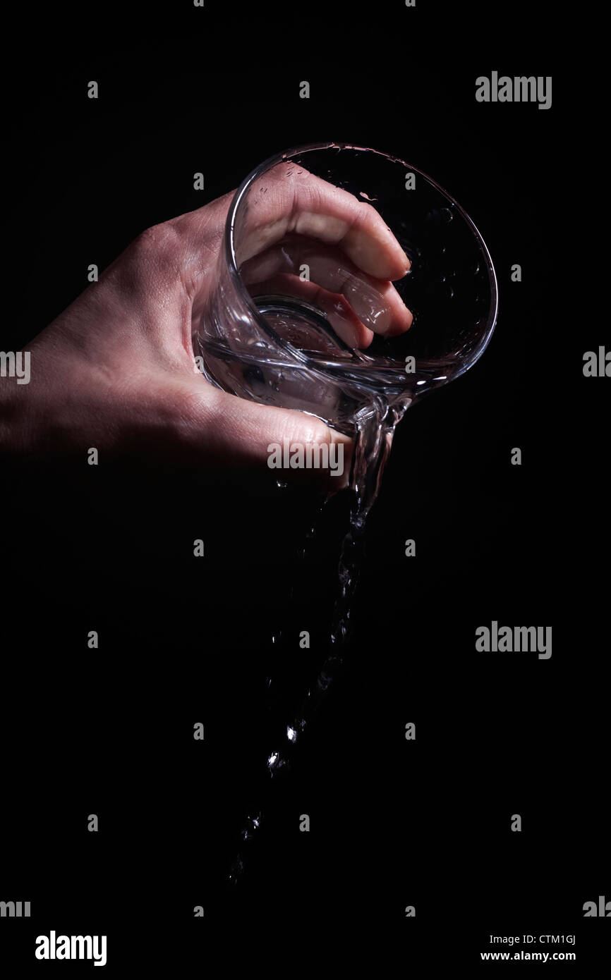 Men's hand poured water from a glass on a black background Stock Photo ...