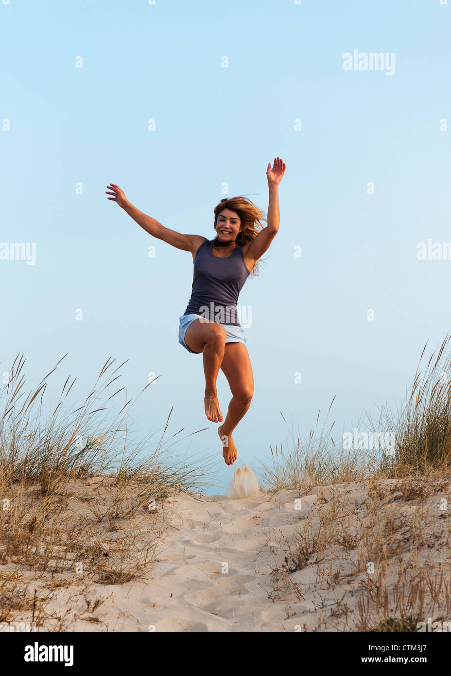 A Young Woman Running And Leaping Down A Sandy Path; Tarifa, Cadiz ...