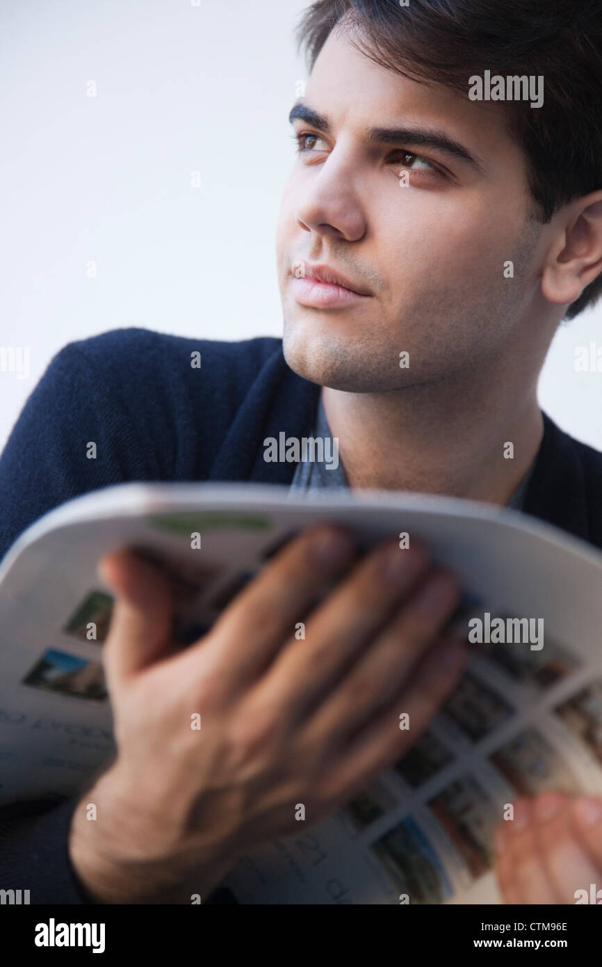 Handsome young man holding a magazine and looking away Stock Photo - Alamy