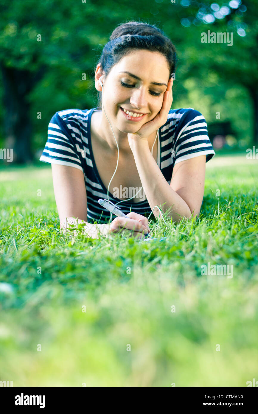 Pretty young college student thinking and writing while listening to ...