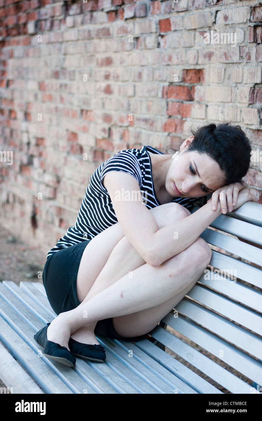 Depressed young woman sitting on a bench in an urban area Stock Photo ...