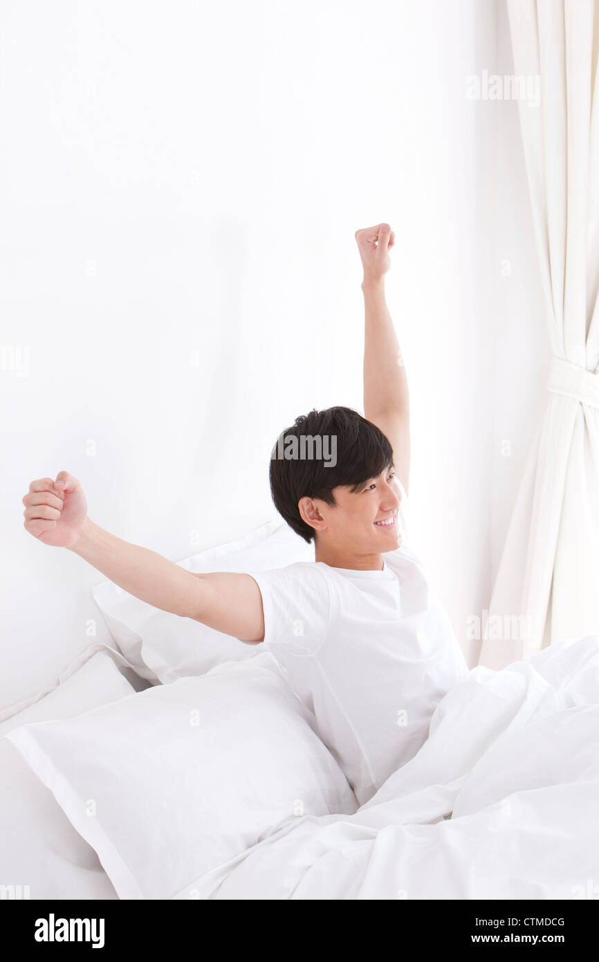 Young man giving a stretch in bed Stock Photo - Alamy
