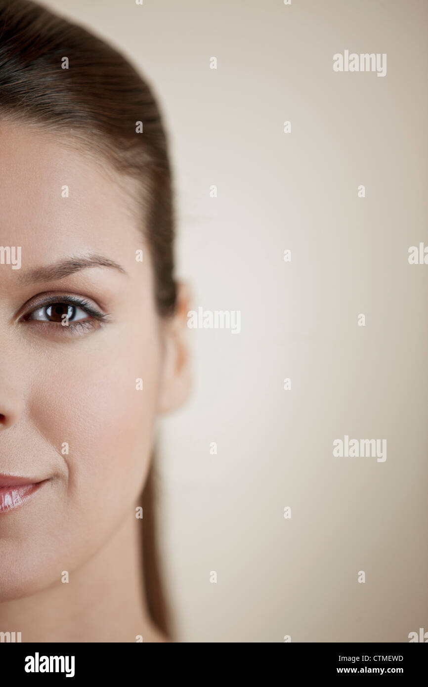 Portrait of a young brunette woman smiling, showing the left half of ...