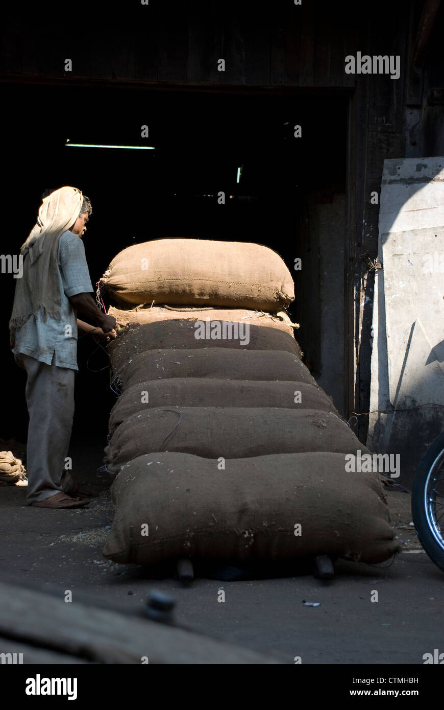 Man sewing up sacks containing cotton - Crawford market, Mumbai ...
