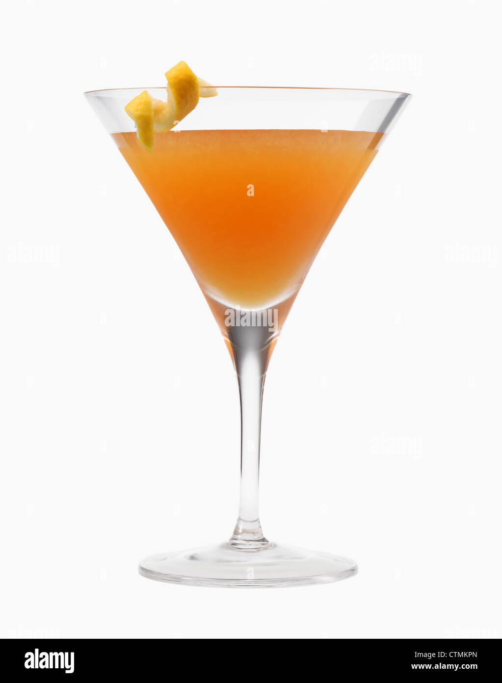 A stemmed cocktail glass with an orange liquid and lemon garnish on a ...