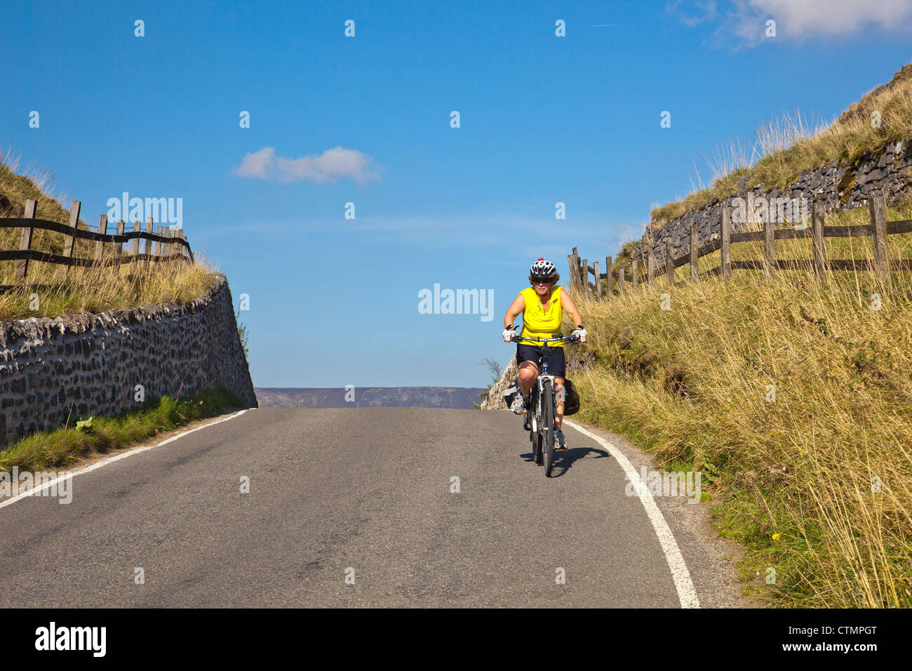 A solitary female cyclist descends the road from Mam Tor into Castleton ...