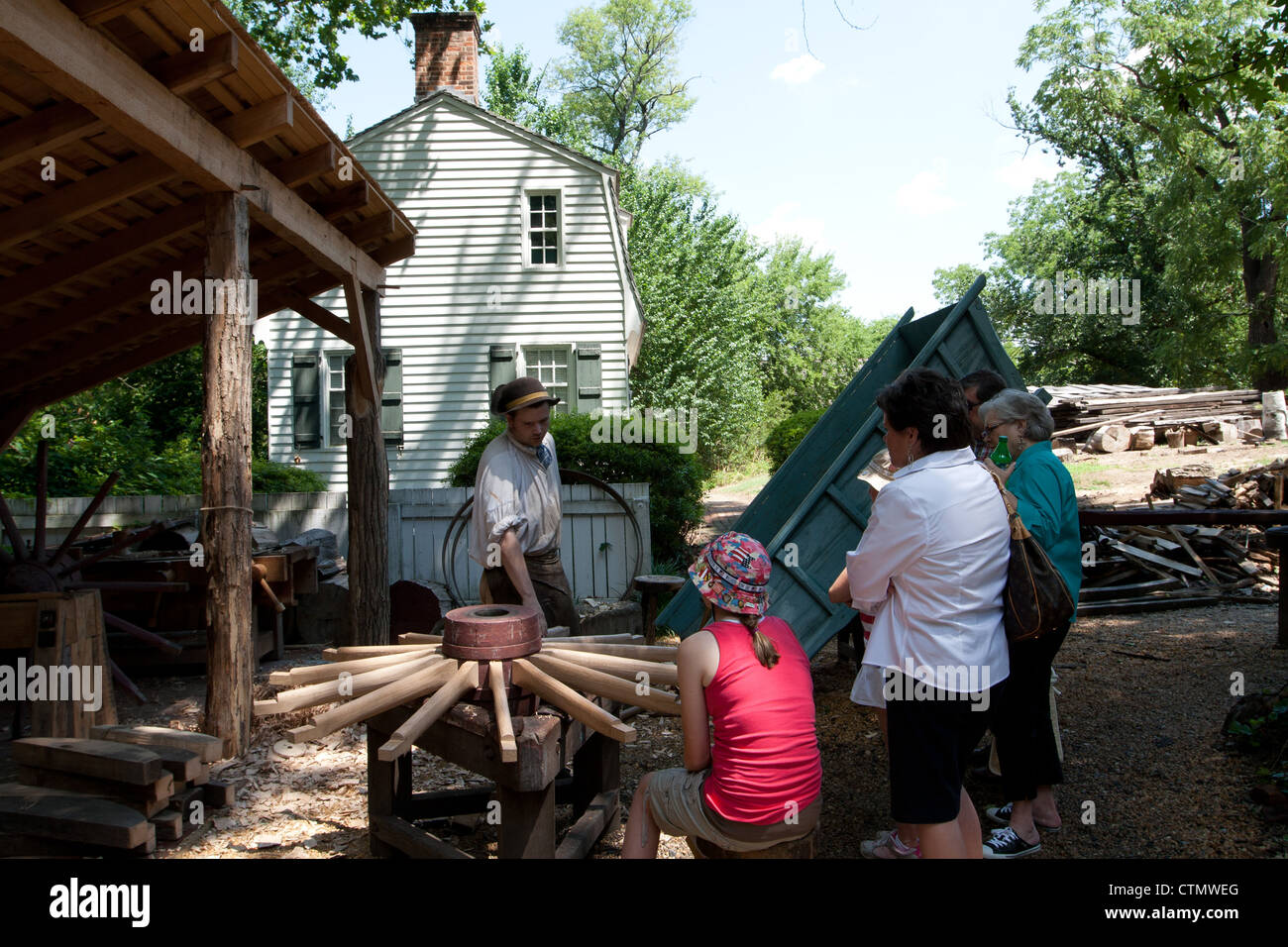 Visitors watch a wheelwright at Colonial Williamsburg, Virginia, USA ...