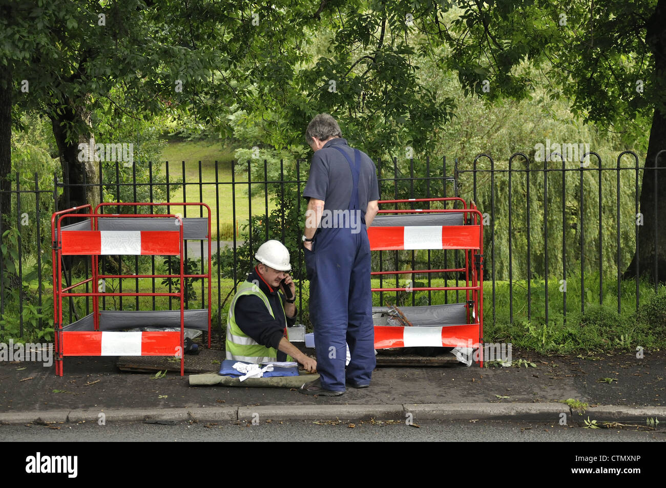 British Telecom engineer working on underground equipment with hazard ...