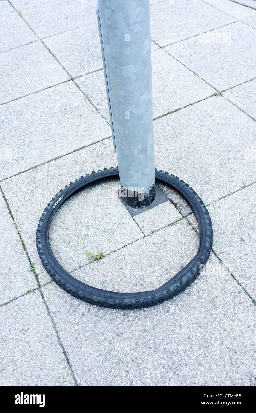 Old bicycle tire on pavement around the base of a lamp post Stock Photo ...