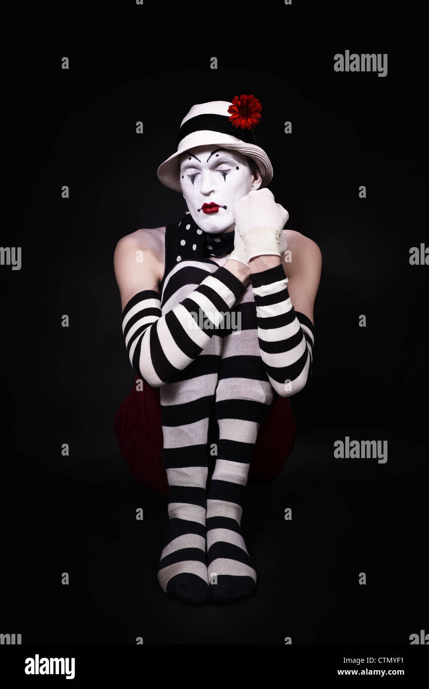 Mime in a white hat sitting on the floor Stock Photo - Alamy