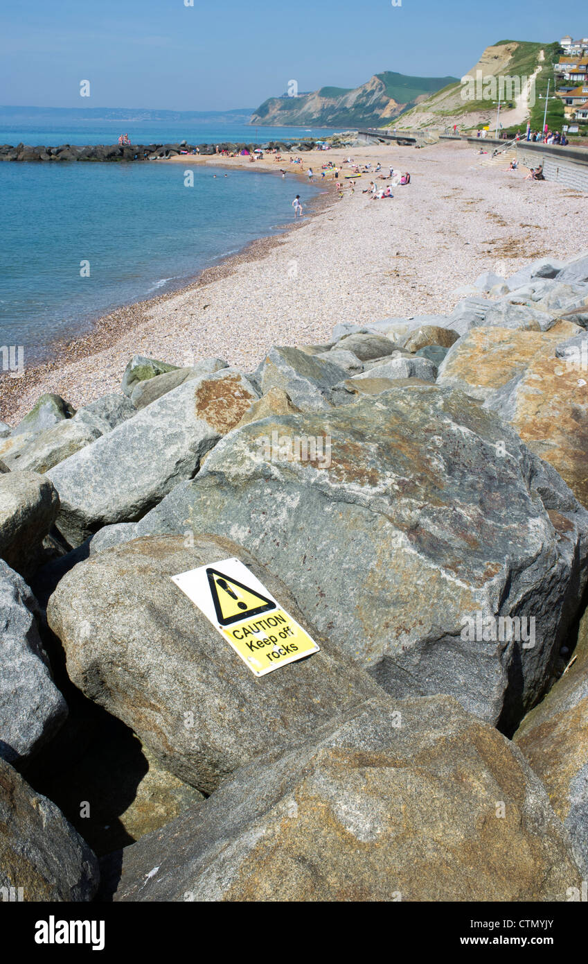 Rocks with caution keep off rocks sign with people on beach and cliffs ...