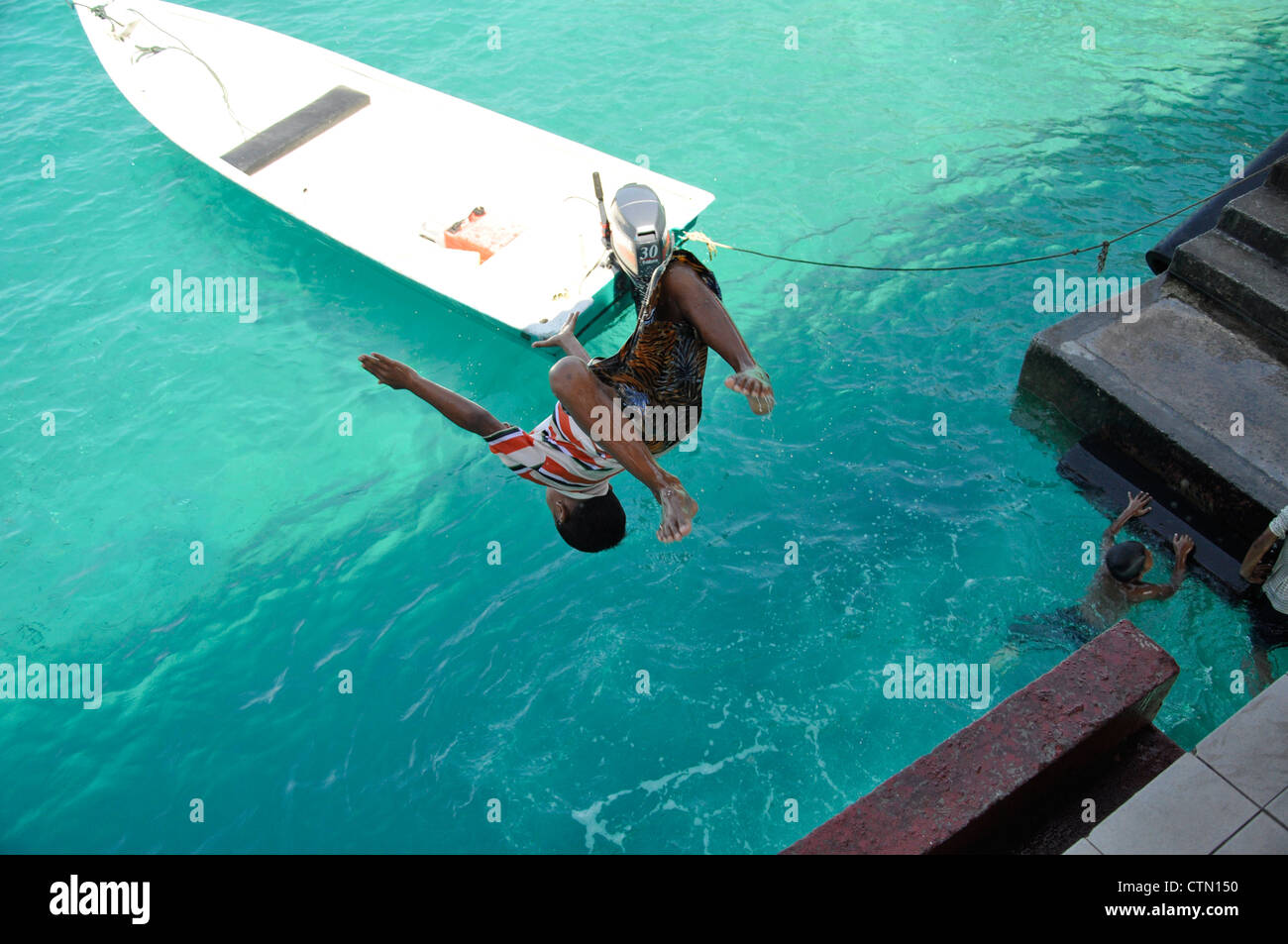Boy jumping from jetty into water with acrobatic act Stock Photo - Alamy