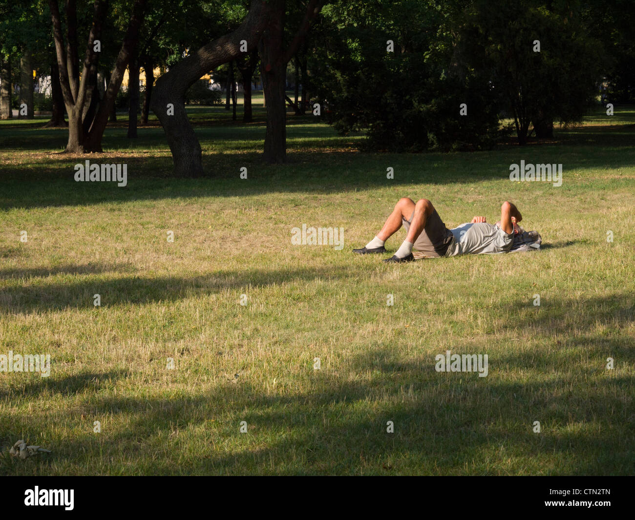 Man lying down resting in a park Stock Photo - Alamy