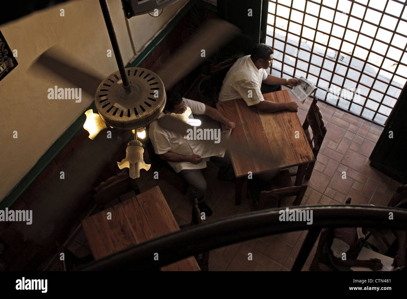 two waiters take a break under a fan in a bar in central havana, cuba ...