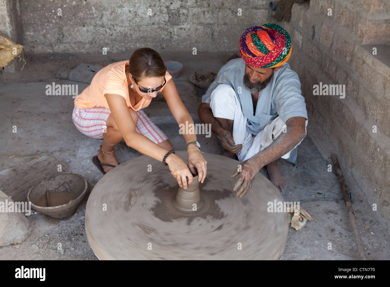 Indian man showing tourist how to make pottery on a wheel in Rajasthan ...