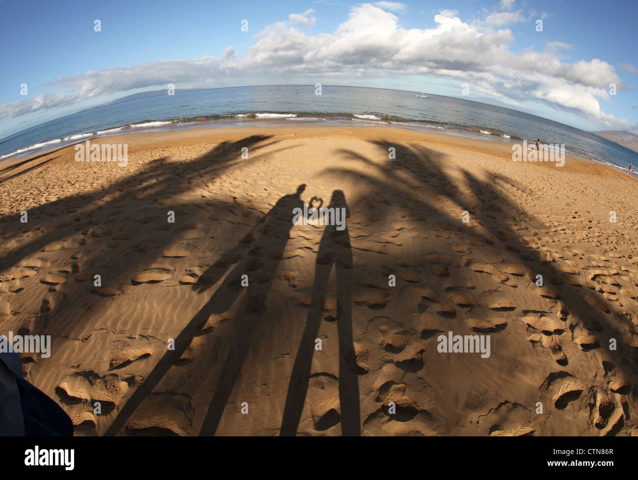 Couple making a heart shape with their hand shadows on a beach, Maui ...
