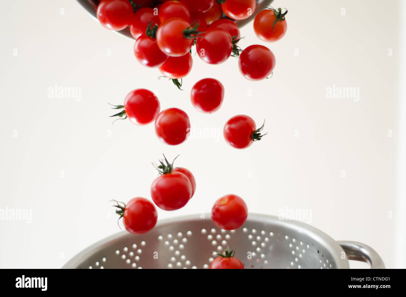 Ripe cherry tomatoes being tumbled and poured down into a silver metal ...