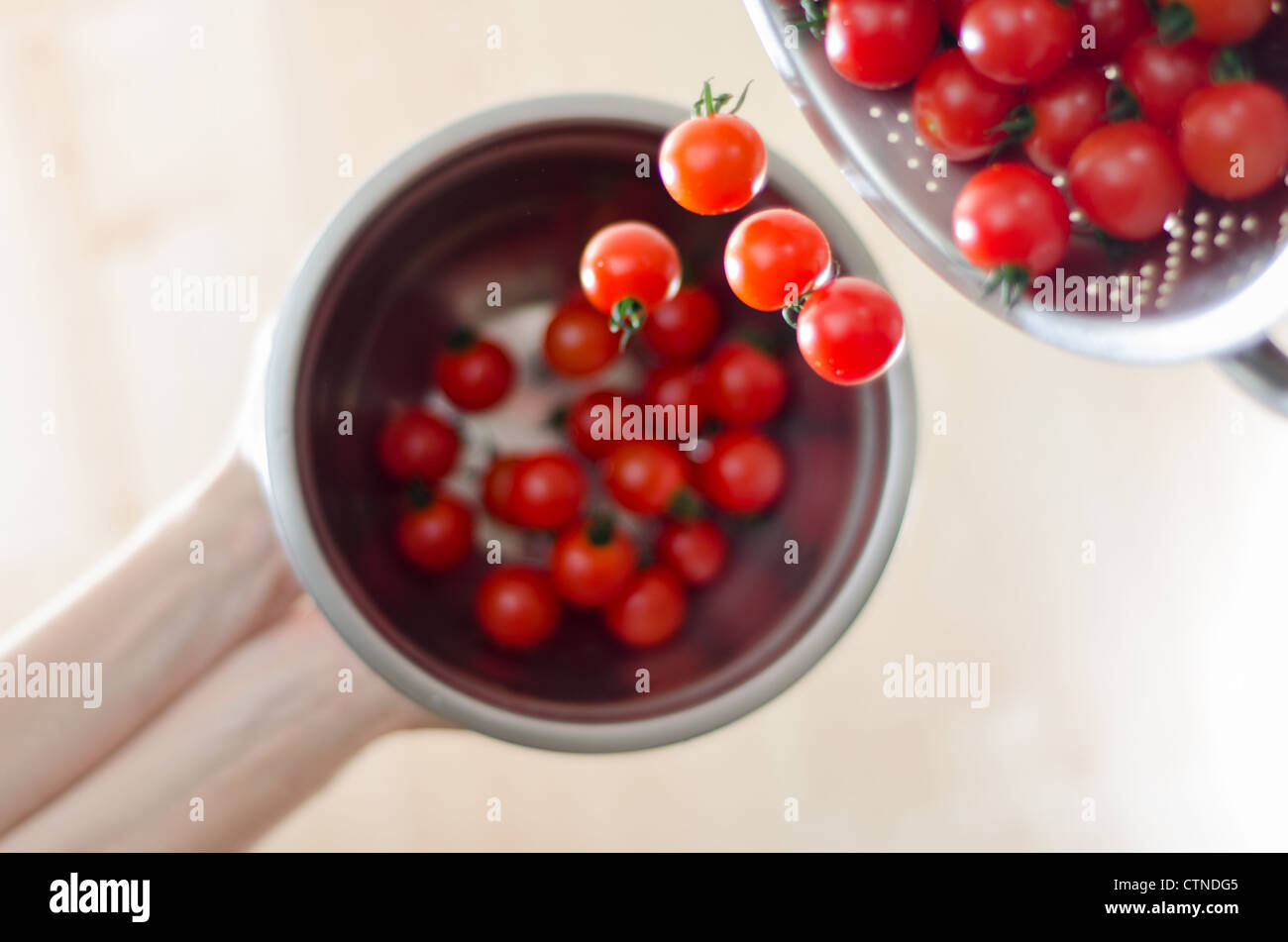Ripe cherry tomatoes being tumbled and poured down into a silver metal ...