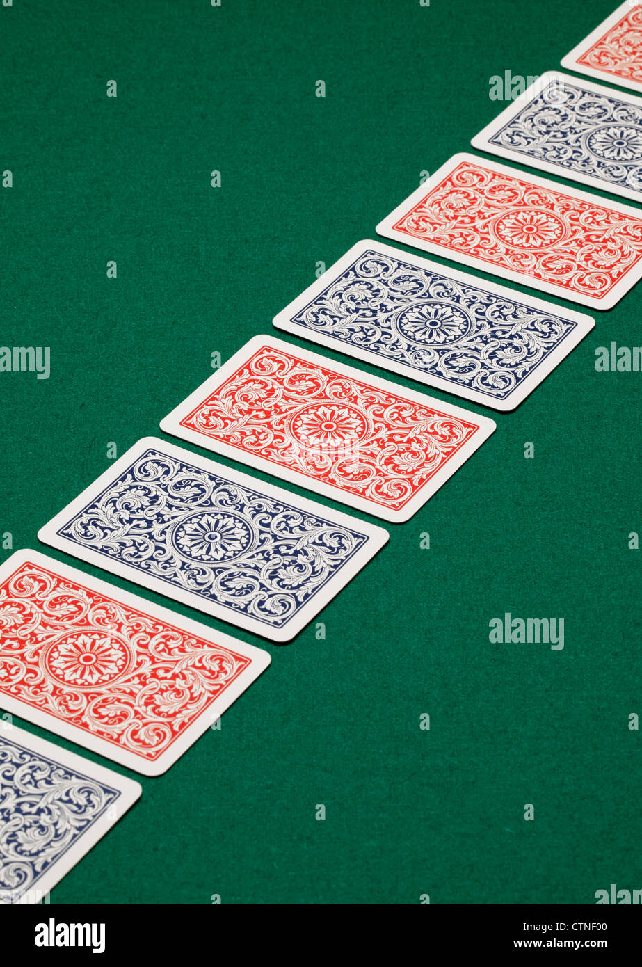 A diagonal line of playing cards on a green table Stock Photo - Alamy