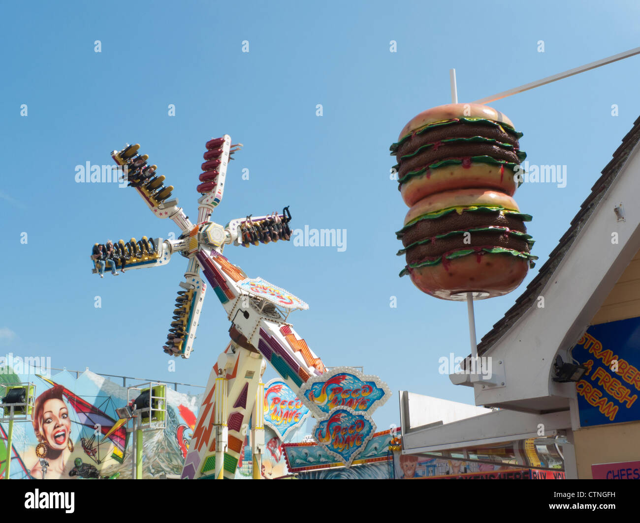 giant beefburger in the sky at a funfair dwarfs a funfair ride against ...