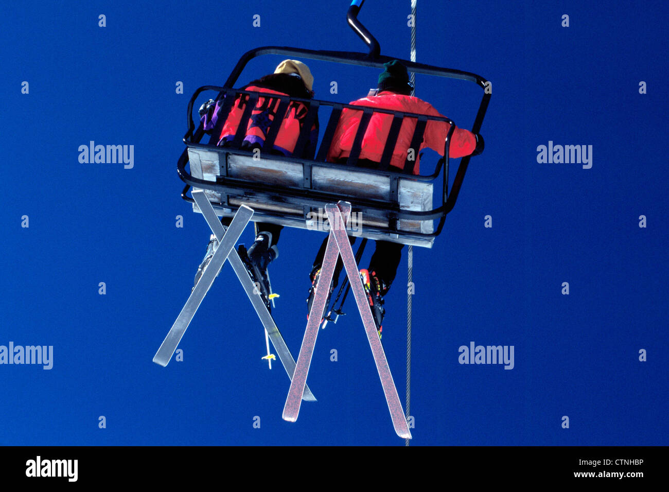 A pair of skiers riding overhead on a ski lift create an abstract image ...