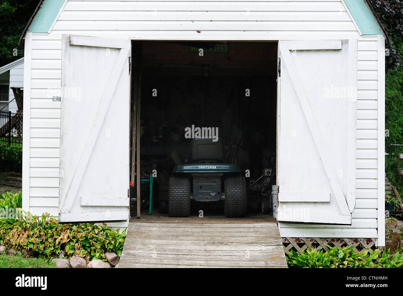 Garden storage shed with lawn tractor Stock Photo - Alamy