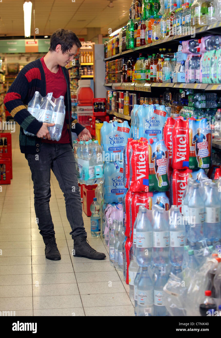 Young man is shopping in a large supermarket. Buying bottled mineral ...