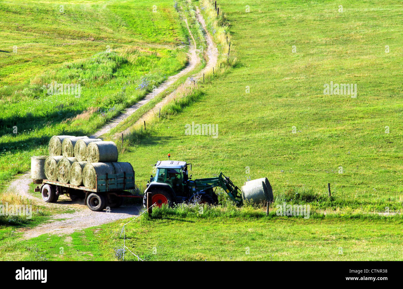 Tractor pulling trailer with bale Stock Photo - Alamy