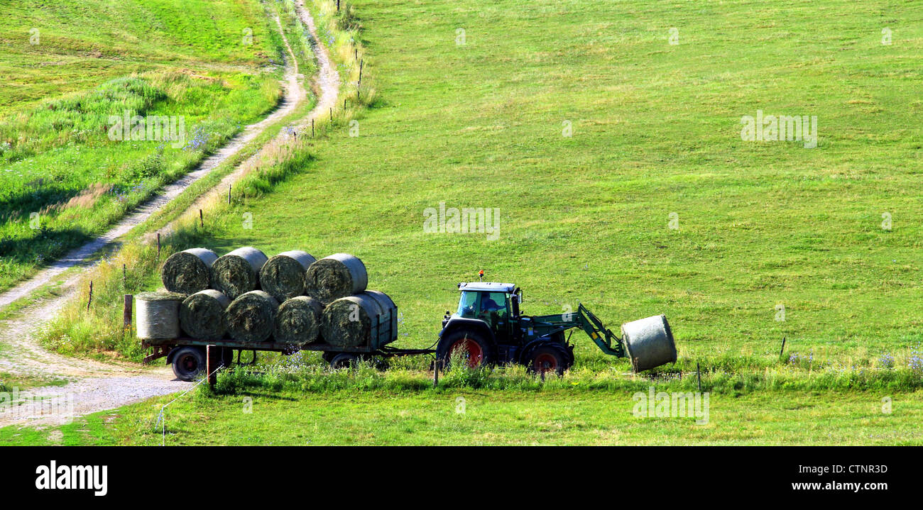 Tractor pulls trailer with bale Stock Photo - Alamy
