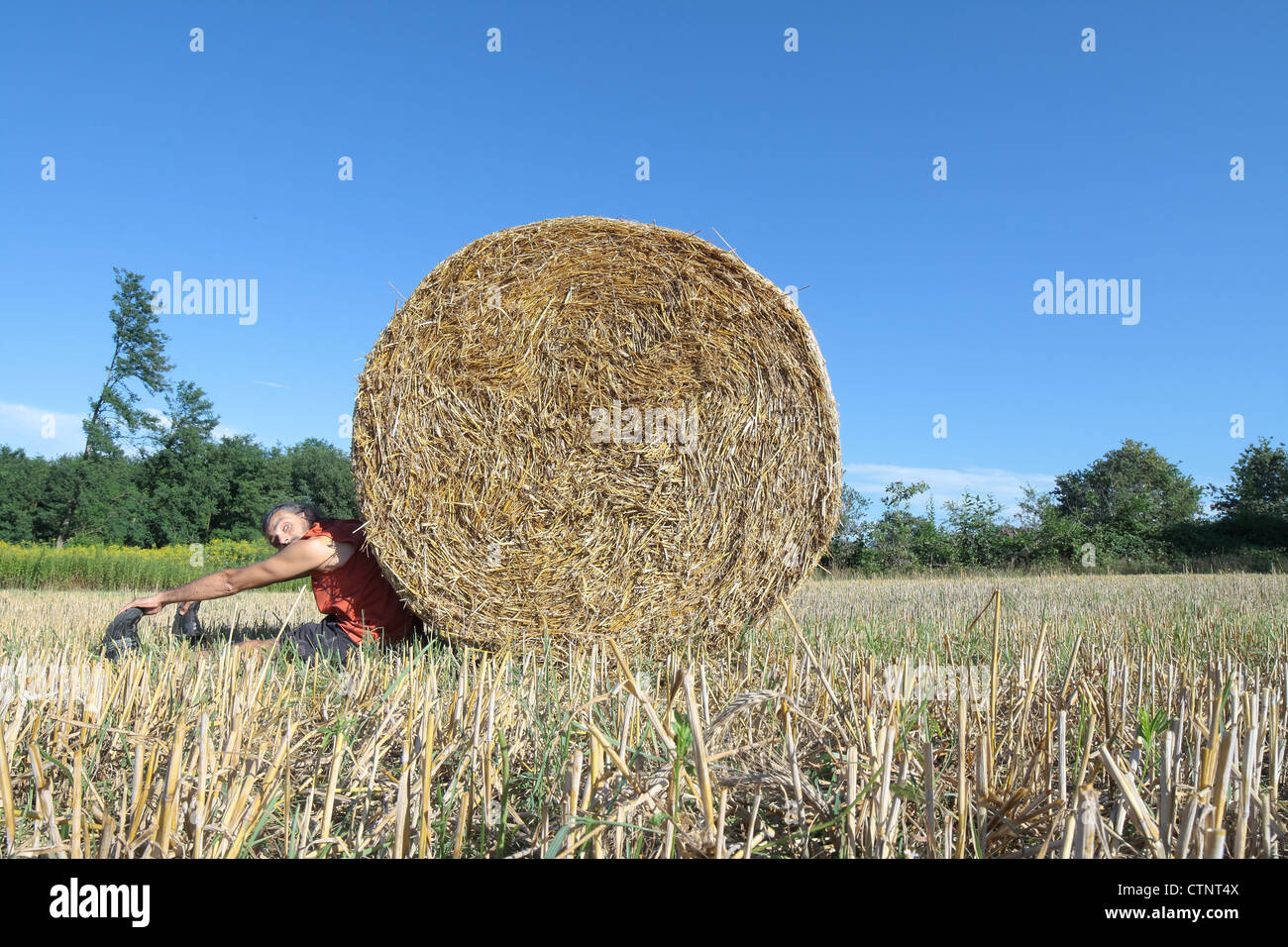 man sitting in a field next to a Hay bale Stock Photo - Alamy