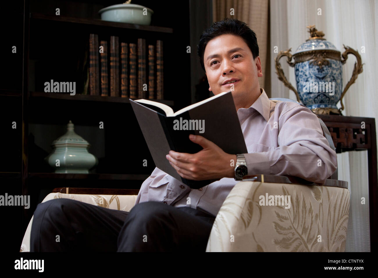 Mature man reading a book in study Stock Photo - Alamy