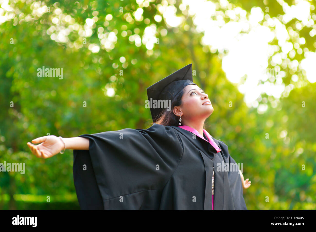 Young Asian Indian female student open arms outdoor on graduation day ...