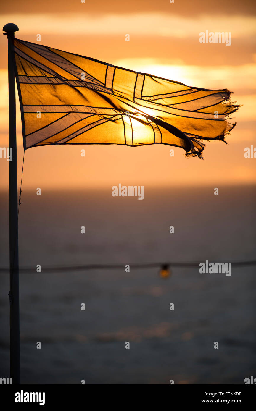 A sunset over an ol tattered semi transparent british flag union jack ...