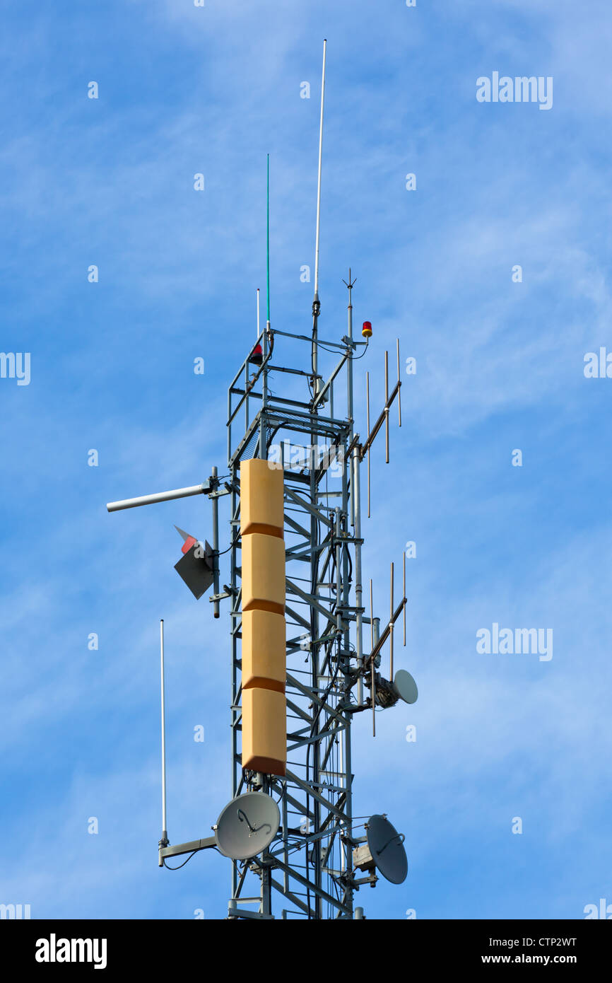 A radio communications tower with dishes against a blue sky Stock Photo ...