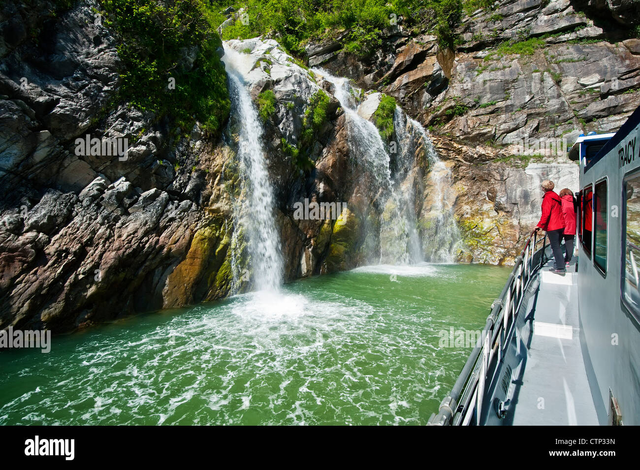 Visitors by the granite walls and waterfalls of a fjord in the Tracy ...