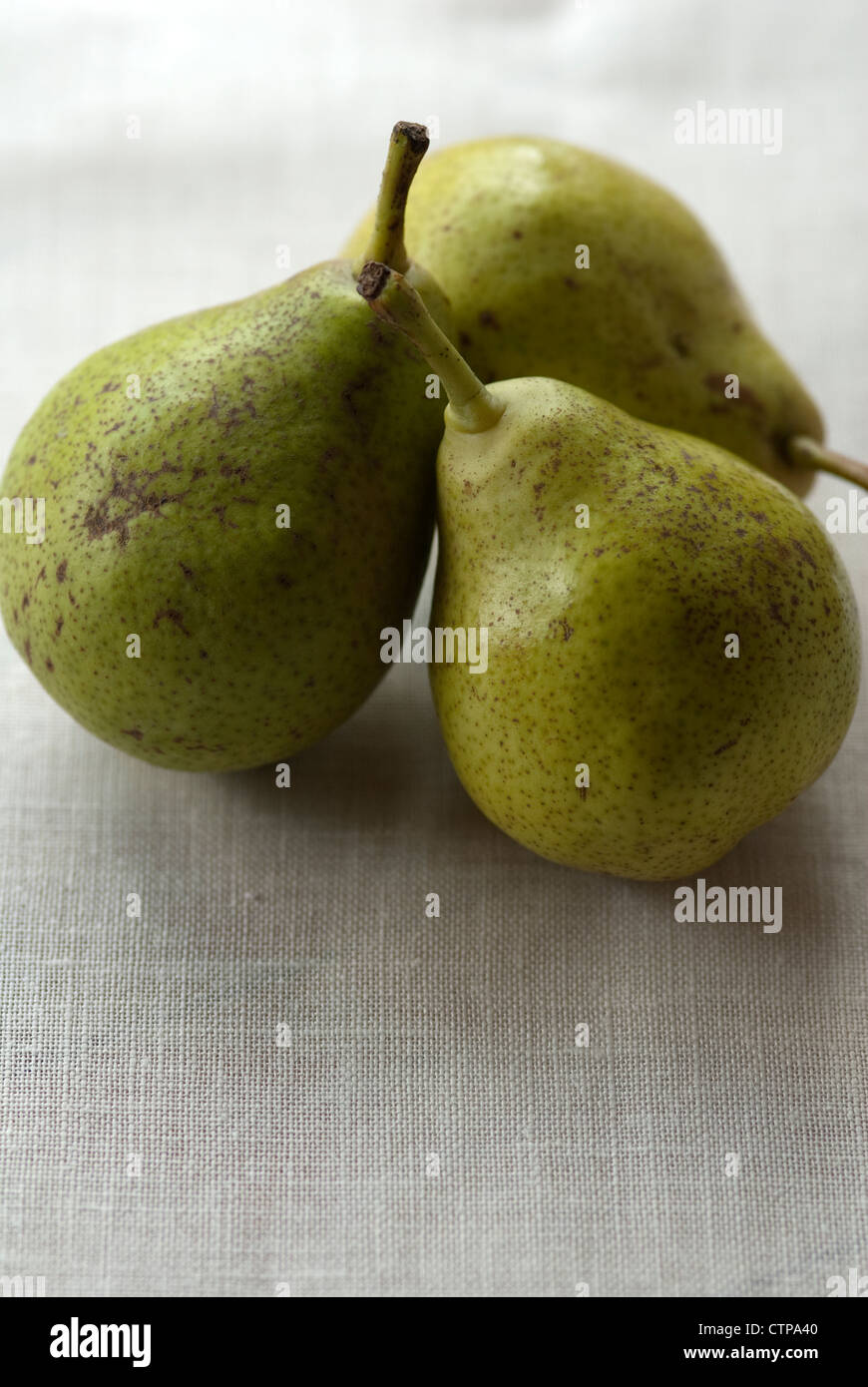 a group of three Guyot pears on a light coloured linen cloth Stock Photo - Alamy