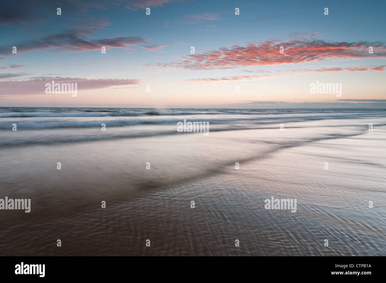 Lines of waves under a pink sky on the beach Stock Photo - Alamy
