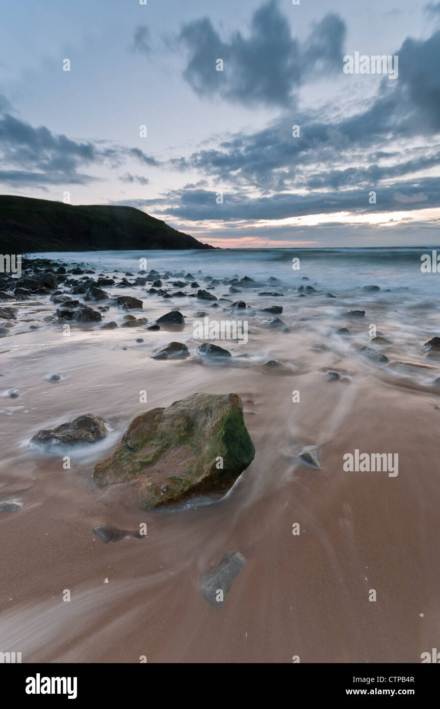 Water rushing past a rock on a beach Stock Photo - Alamy