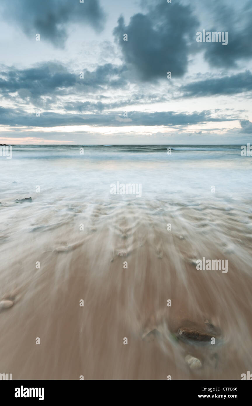 Water rushing out over rocks on a beach Stock Photo - Alamy