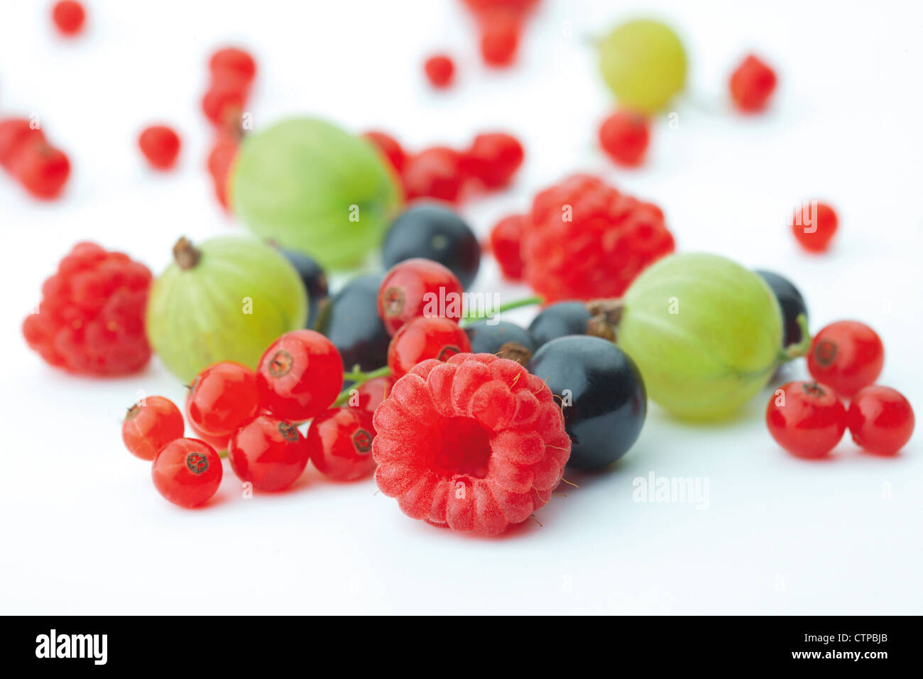 Spilled mixed berries on white background whith a raspberry in the ...